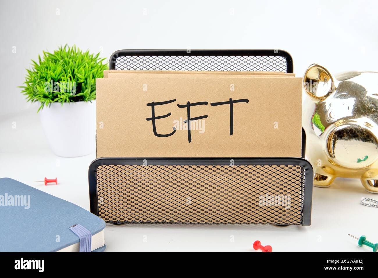 EFT text on paper next to piggy bank, notepad, flower on a white ...