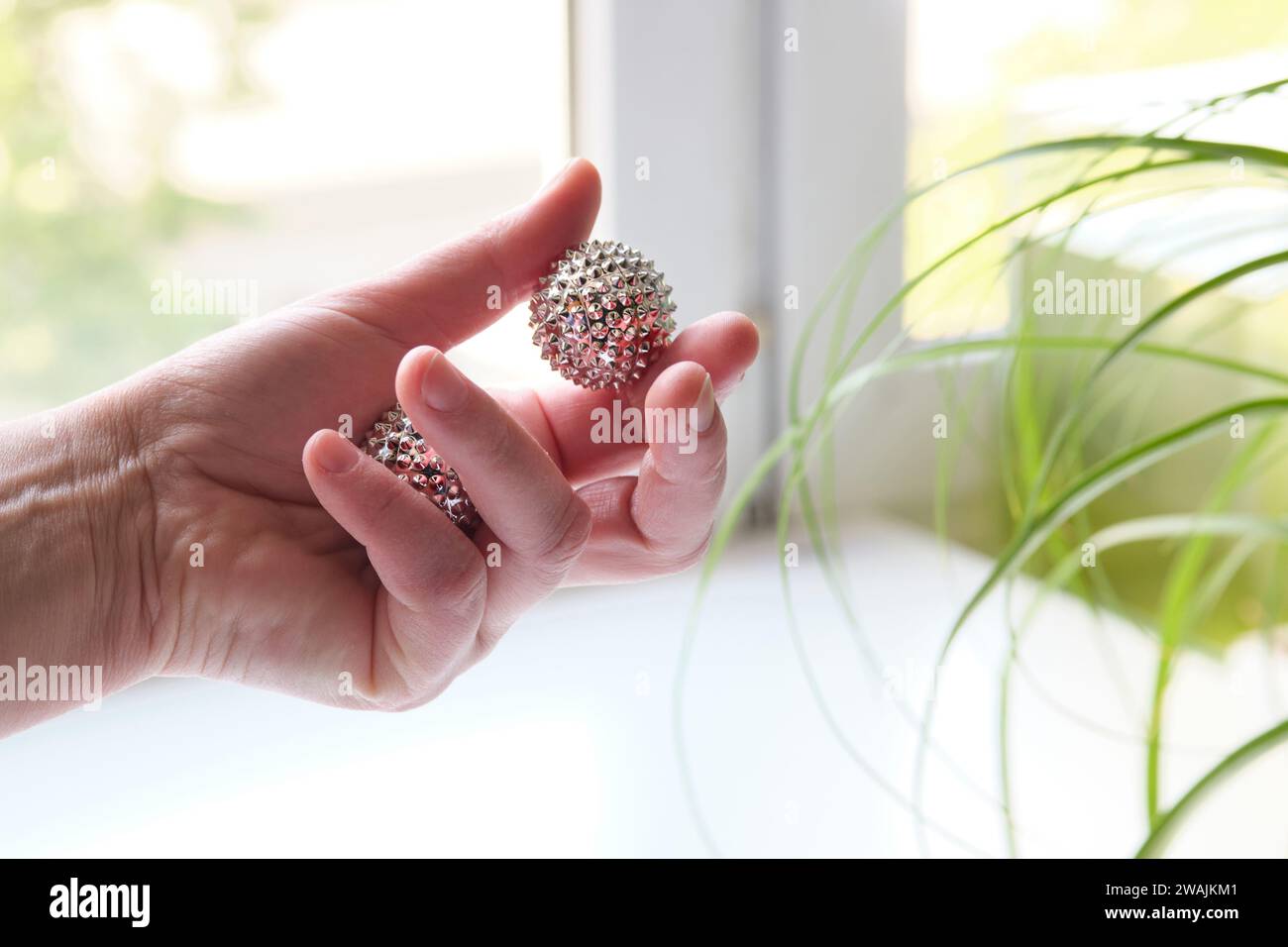 Silver metal magnetic balls in female hand. Spiky tool for hand massage ...