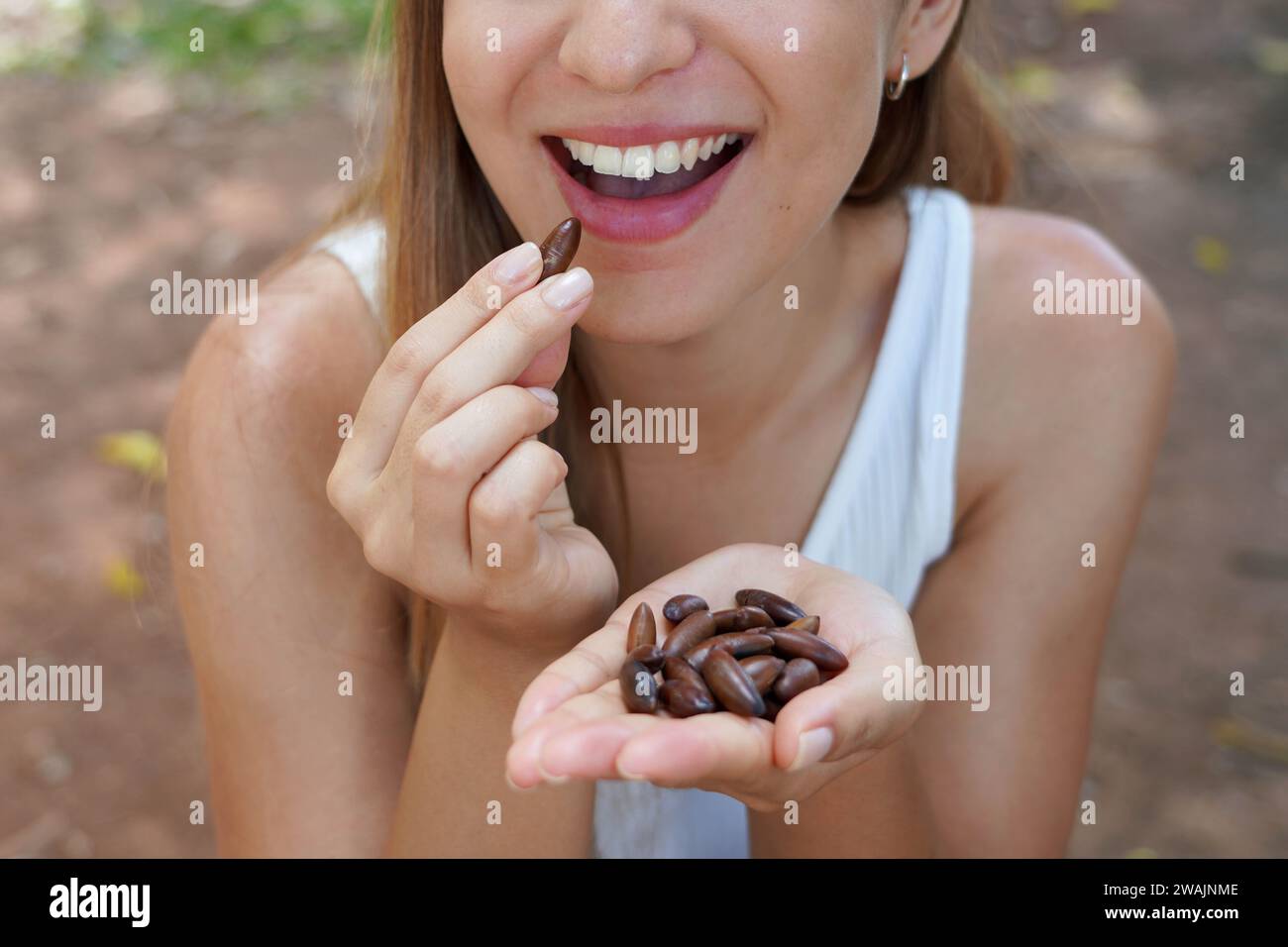 Fitness healthy woman outdoors. Close up of girl eating baru nut seeds ...