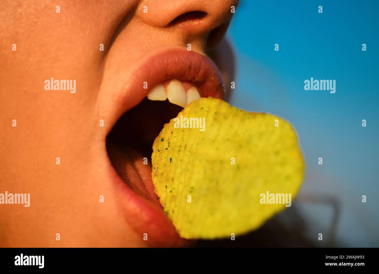Pleasure eating potato chips. Close up female mouth eat potato chips ...