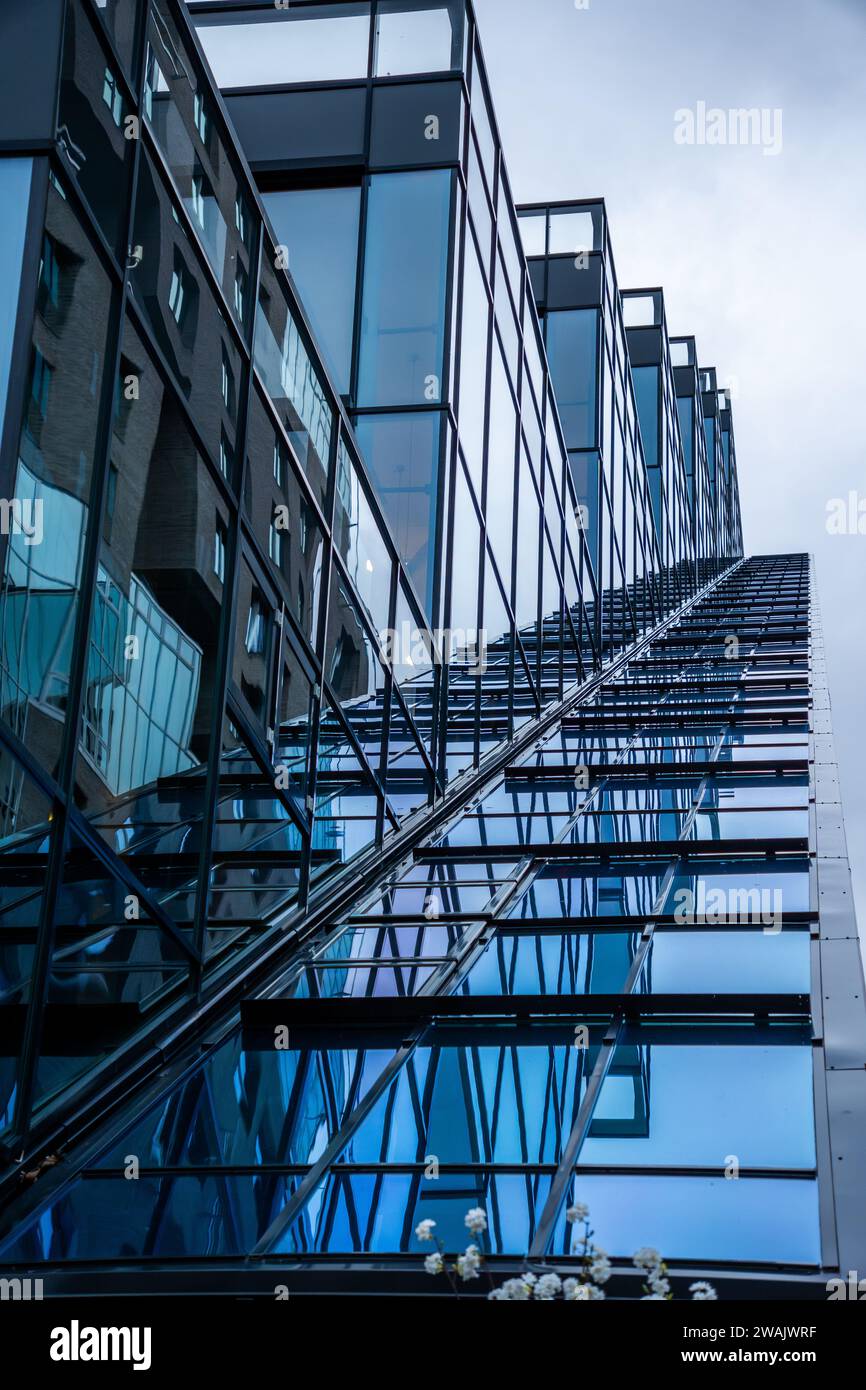 A contemporary tall building features a striking blue glass facade ...
