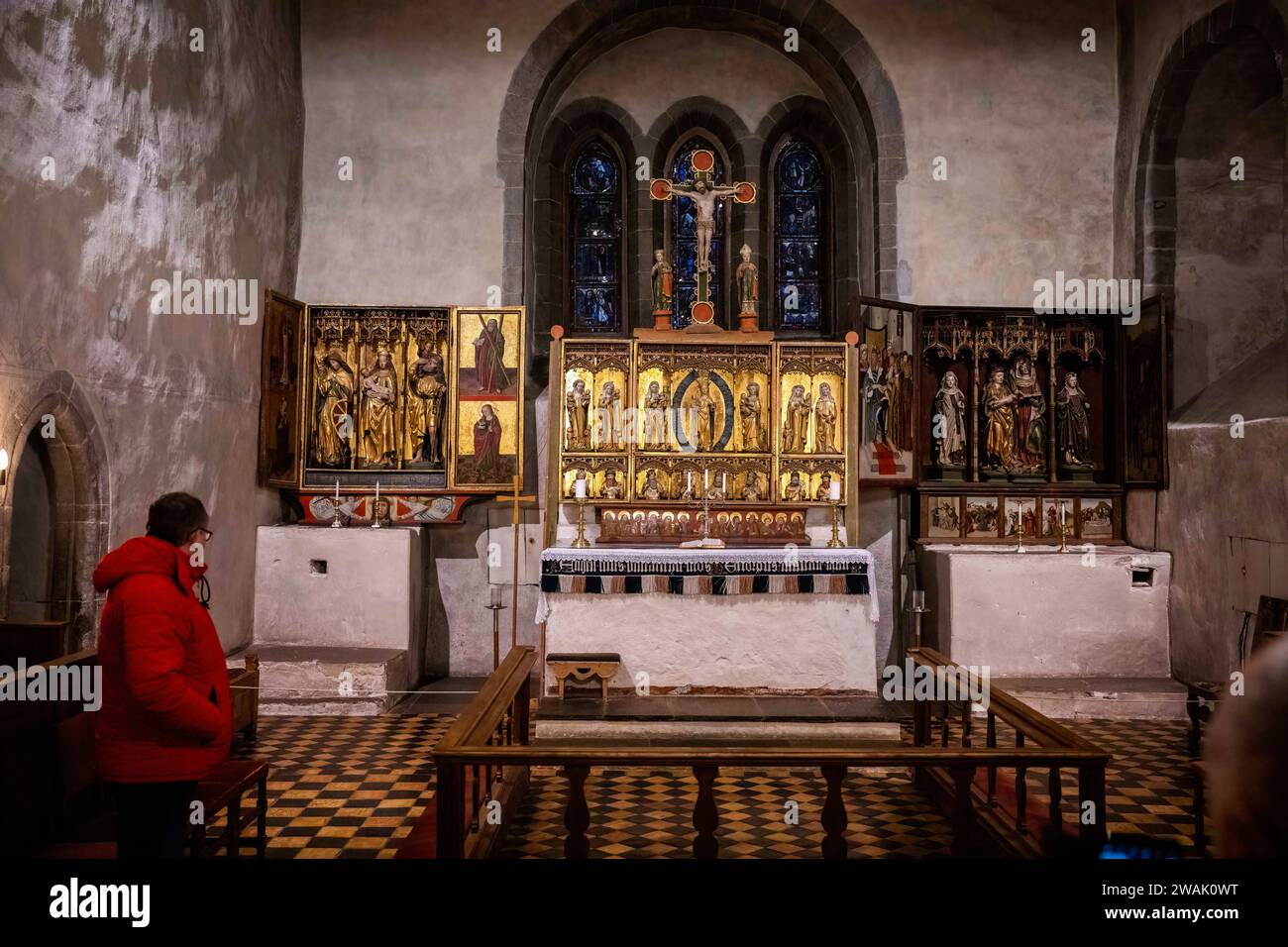 A tourist walks around the main altar of the medieval church of ...