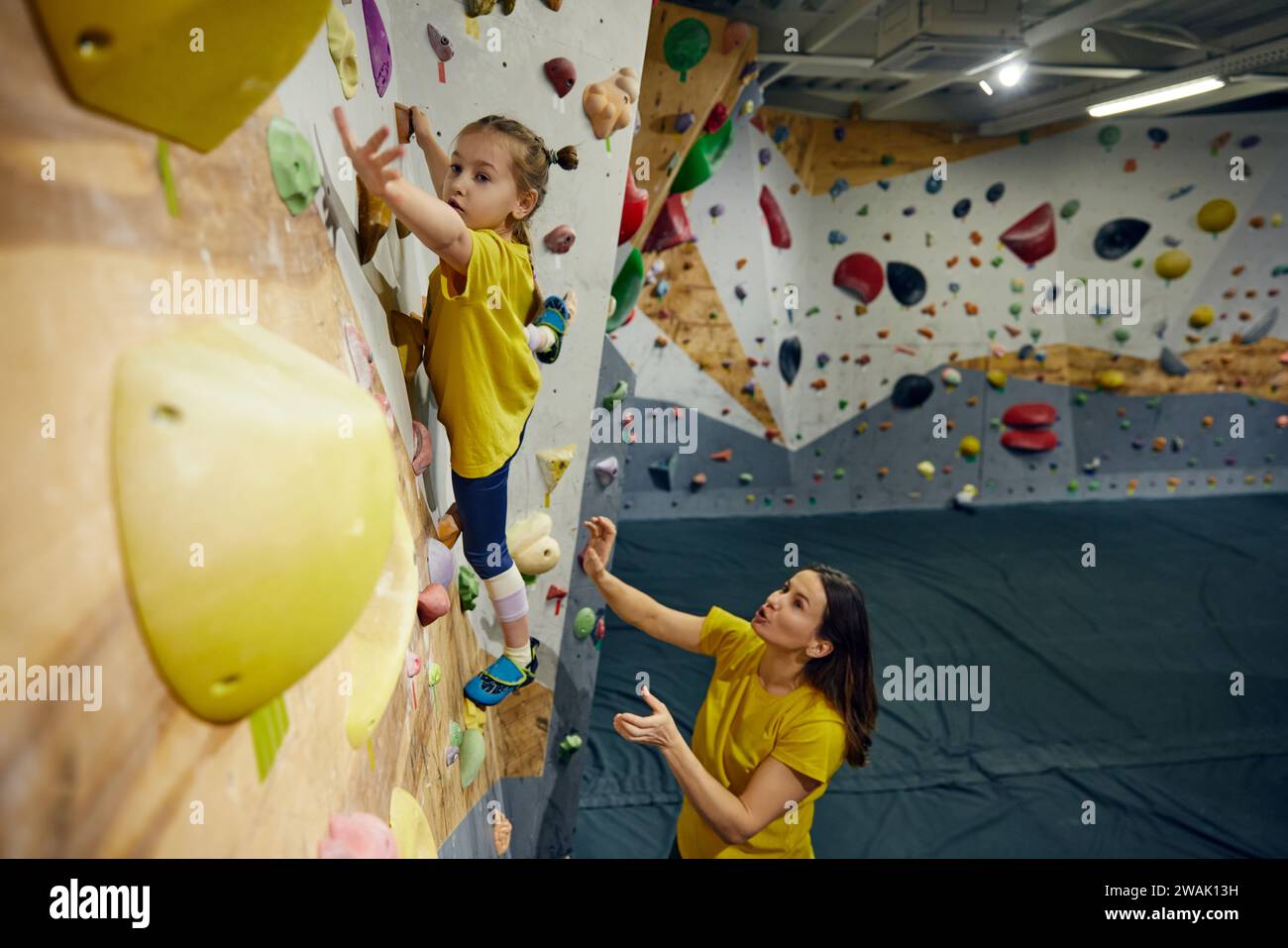 Little girl, child training with instructor, practicing bouldering ...
