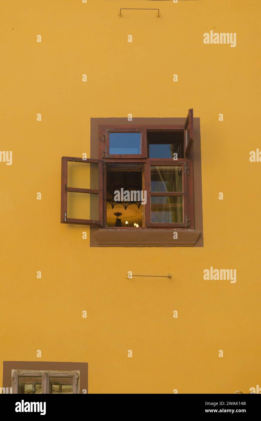 Medieval house yellow painted wall with an opened old wooden window ...