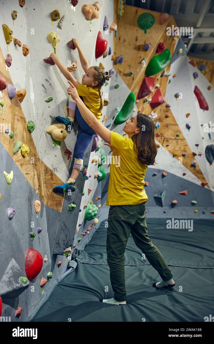 Little girl, child training with instructor, practicing bouldering ...
