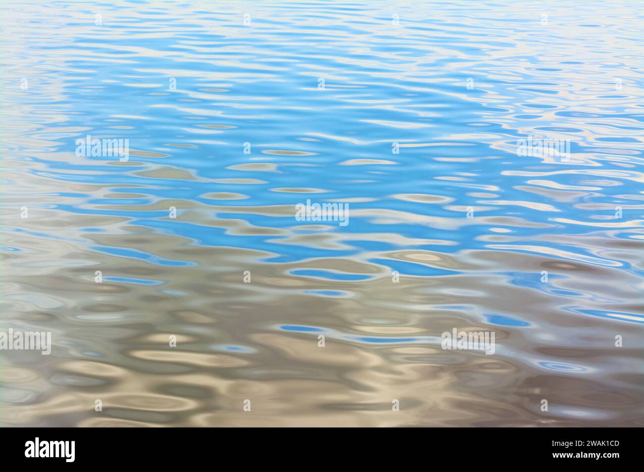 Light patterns on water reflecting cloud and sky with colours of blue ...