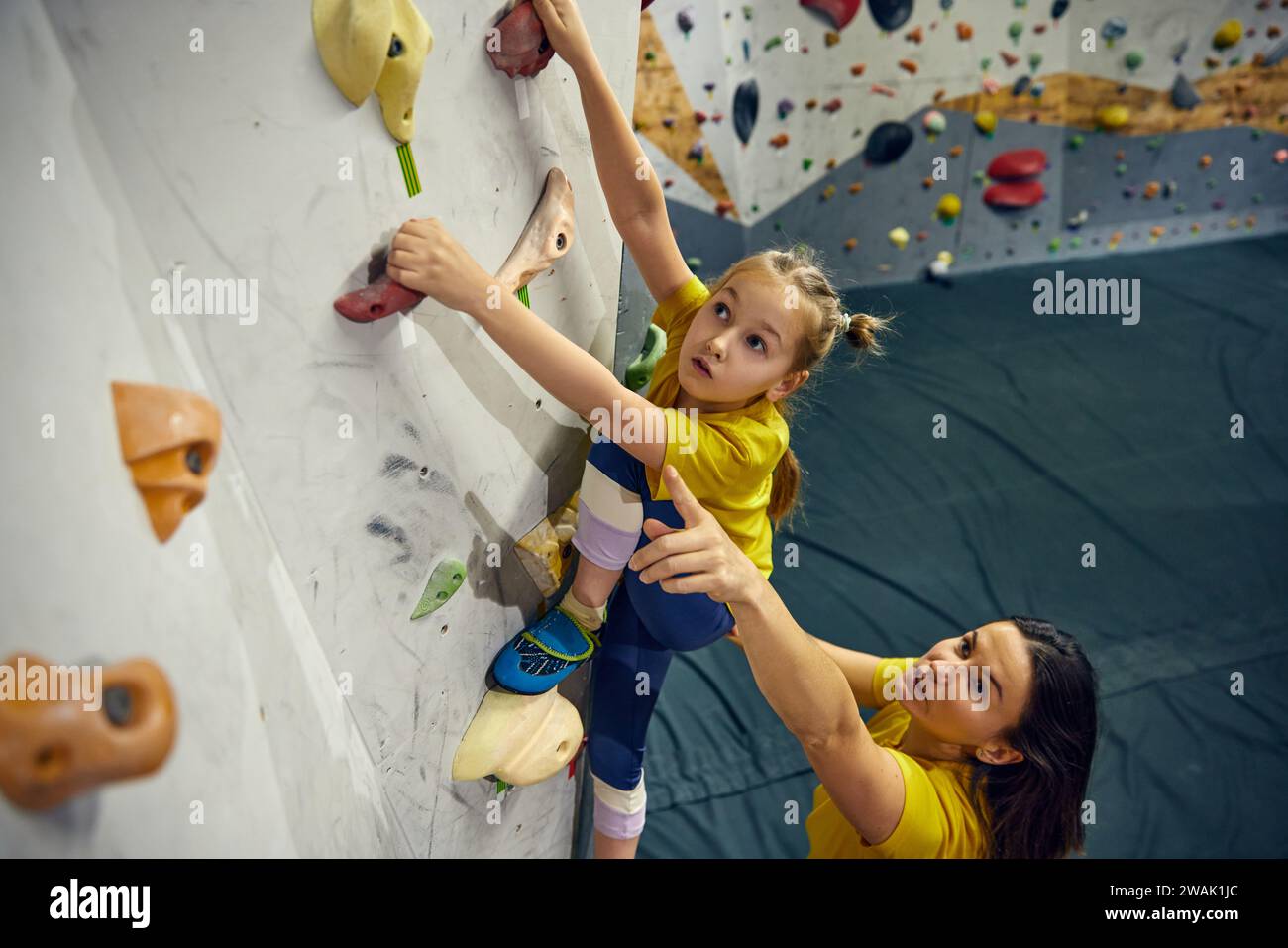 Little girl, child practicing bouldering, training with instructor ...