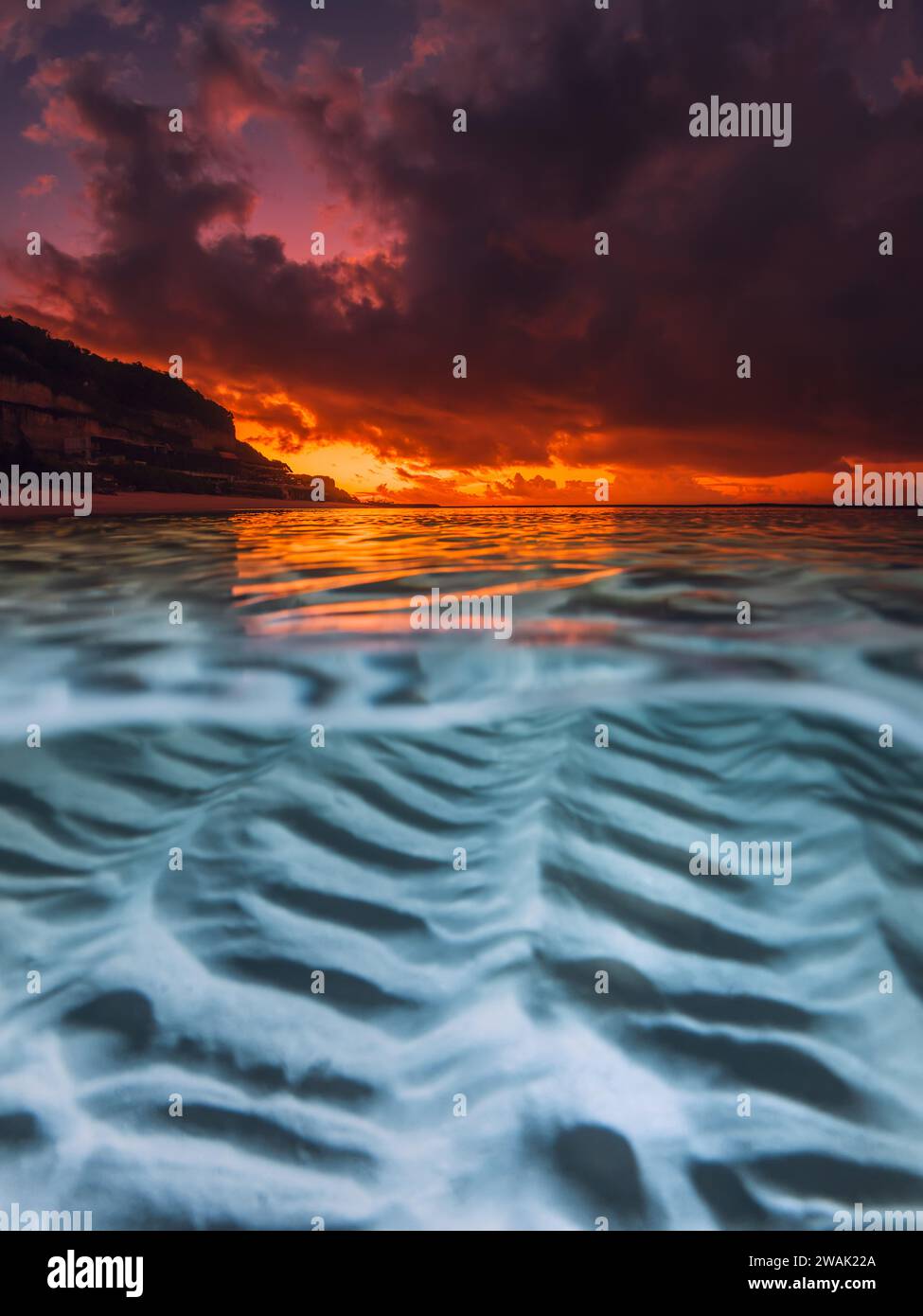 Split view with bright sunset and underwater sandy sea bottom in ...