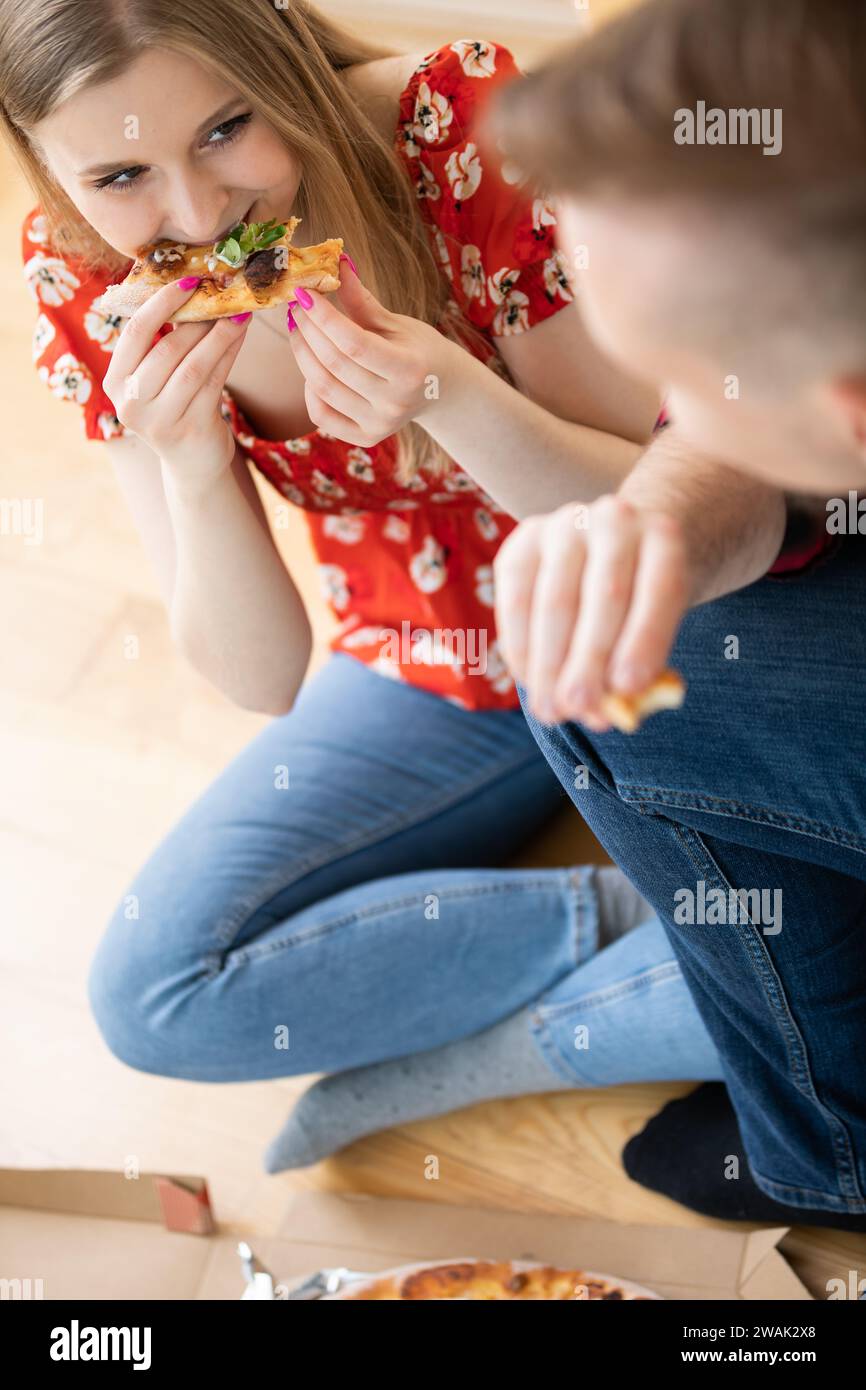 The girl looks at her boyfriend while biting into a slice of pizza ...
