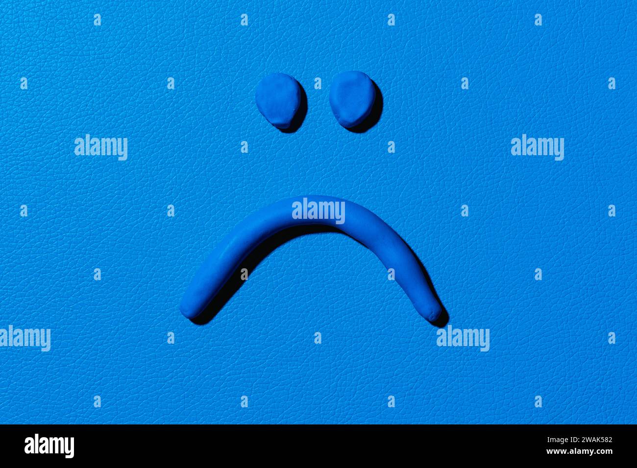 a sad face made with blue modelling clay on a blue background Stock ...