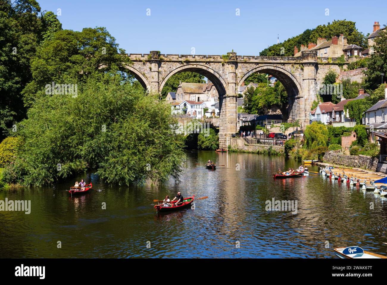 Tourists in hired rowing boats on the River Nidd with the railway ...