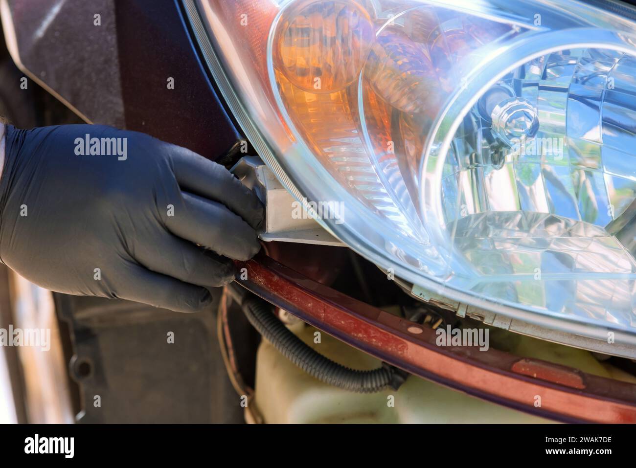 Car mechanic assembling headlight on car during repair Stock Photo - Alamy