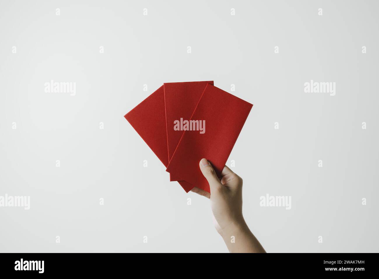A hand holds angpao or red monetary gift on white background. Chinese ...