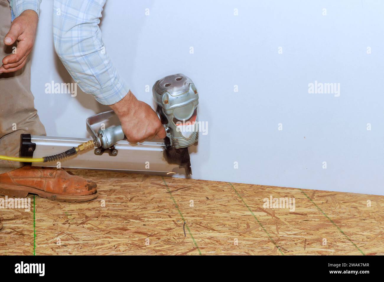 Using an air nail gun to install wooden plywood for new floor Stock ...