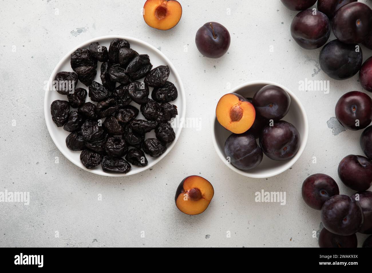 Dried prunes and ripe raw plums on light background Stock Photo - Alamy