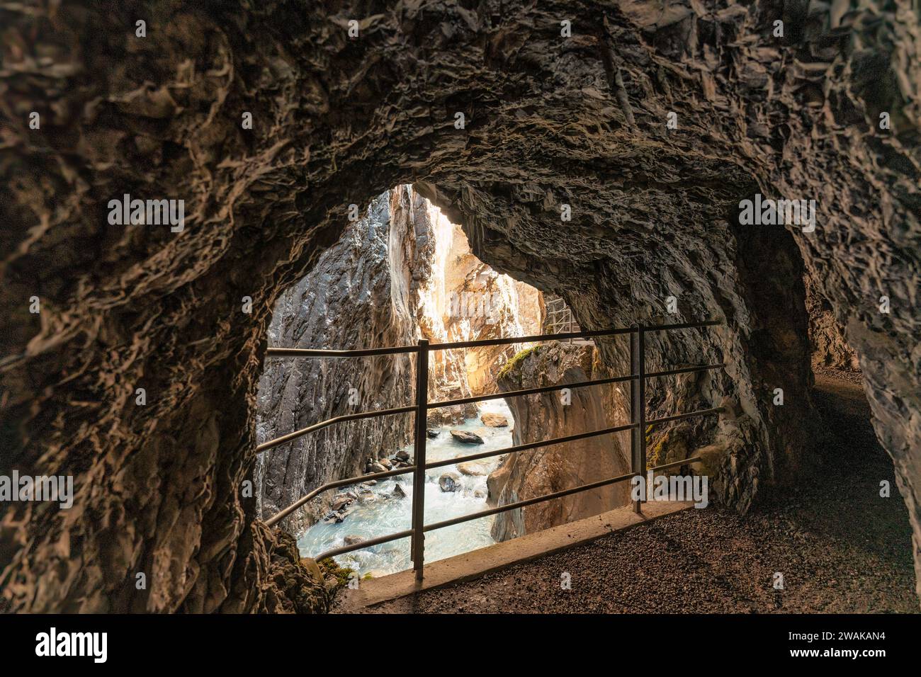 Natural limestone cave with stream flowing in Rosenlaui glacier gorge ...