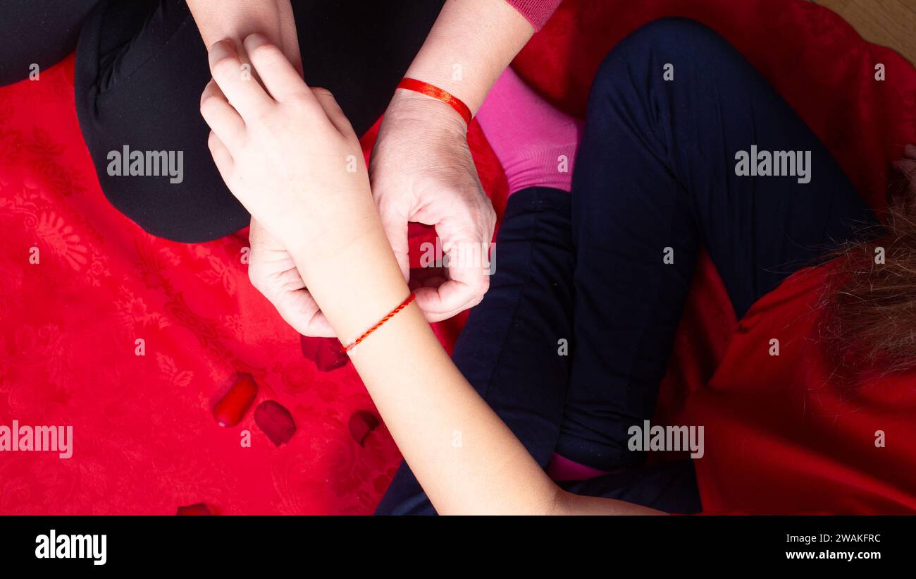 Mother tiying red ribbon for her daughter on her first period. Menarche ...