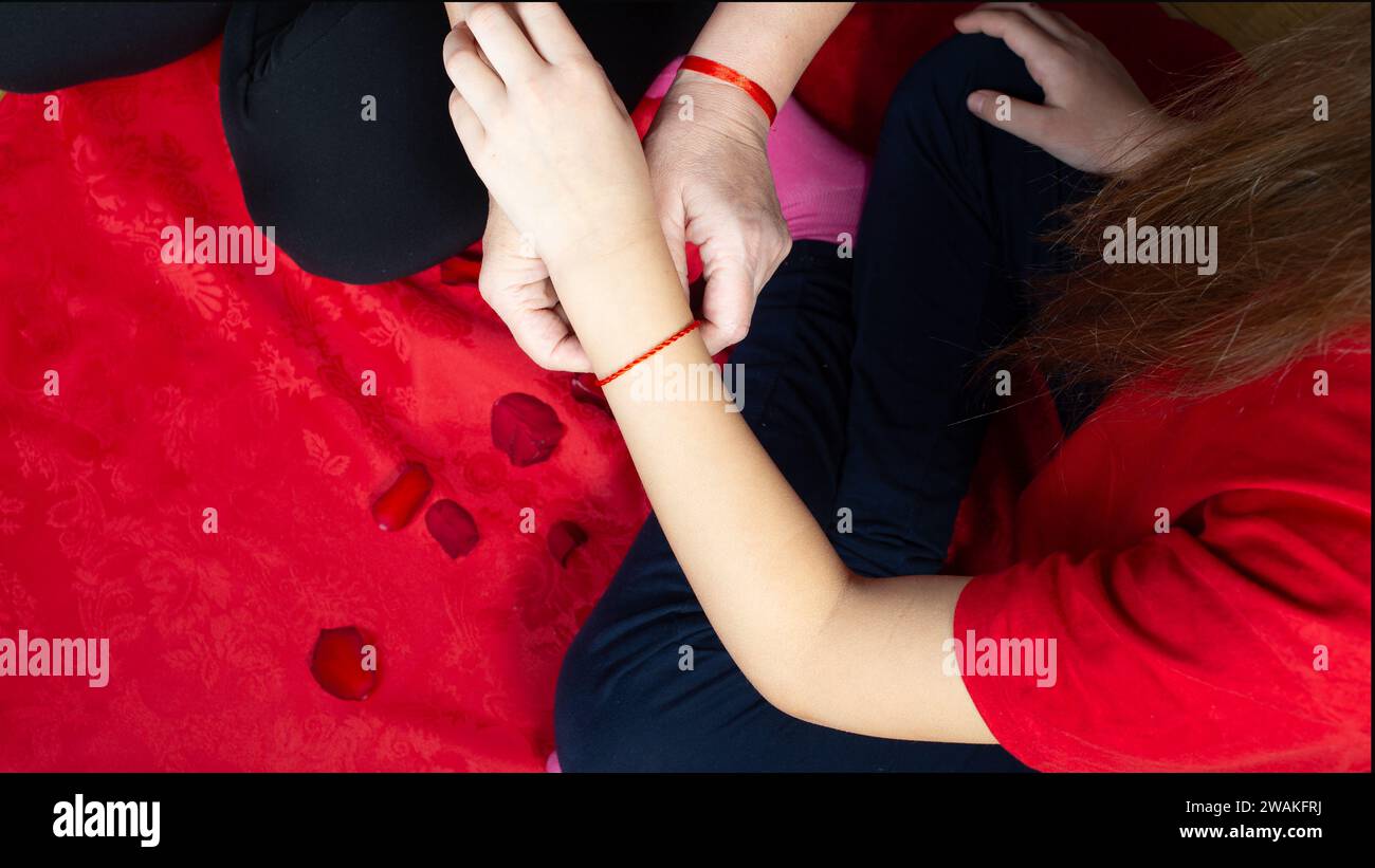 Mother tiying red ribbon for her daughter on her first period. Menarche ...