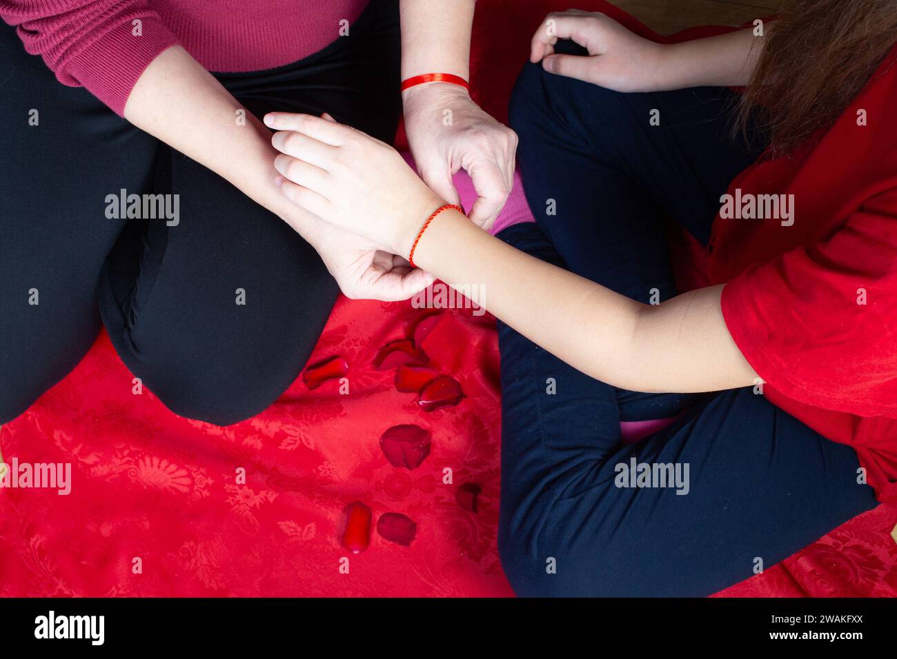 Mother tiying red ribbon for her daughter on her first period. Menarche ...