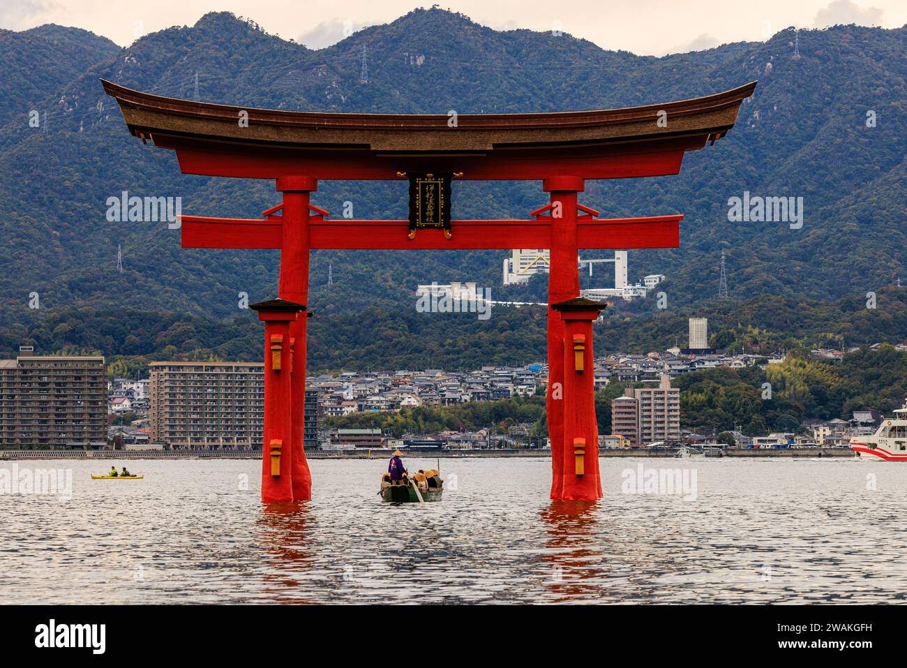 a small boat rows through the famous floating red torii gate of ...