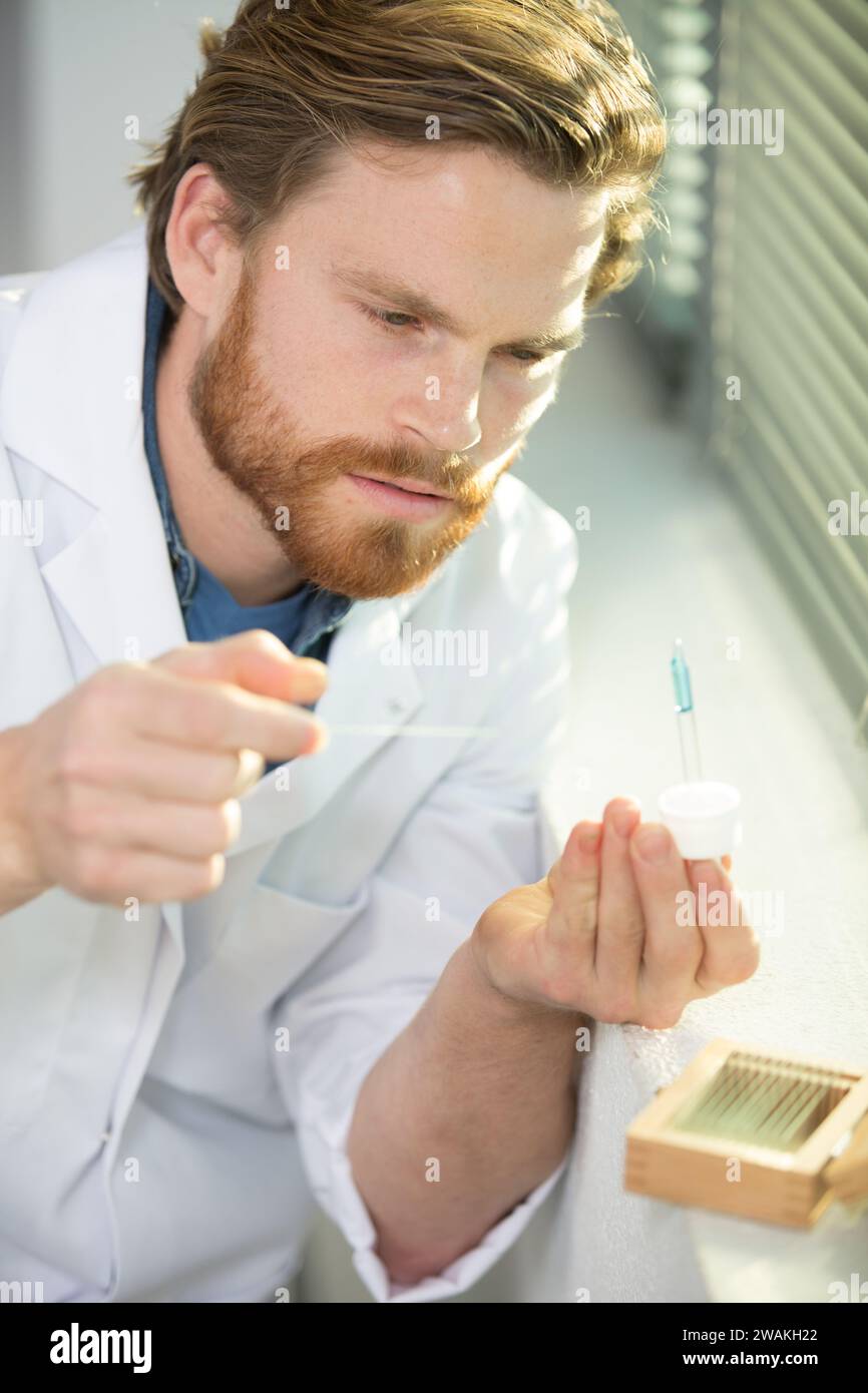 male chemical scientist place sample of liquid on microscope slide ...