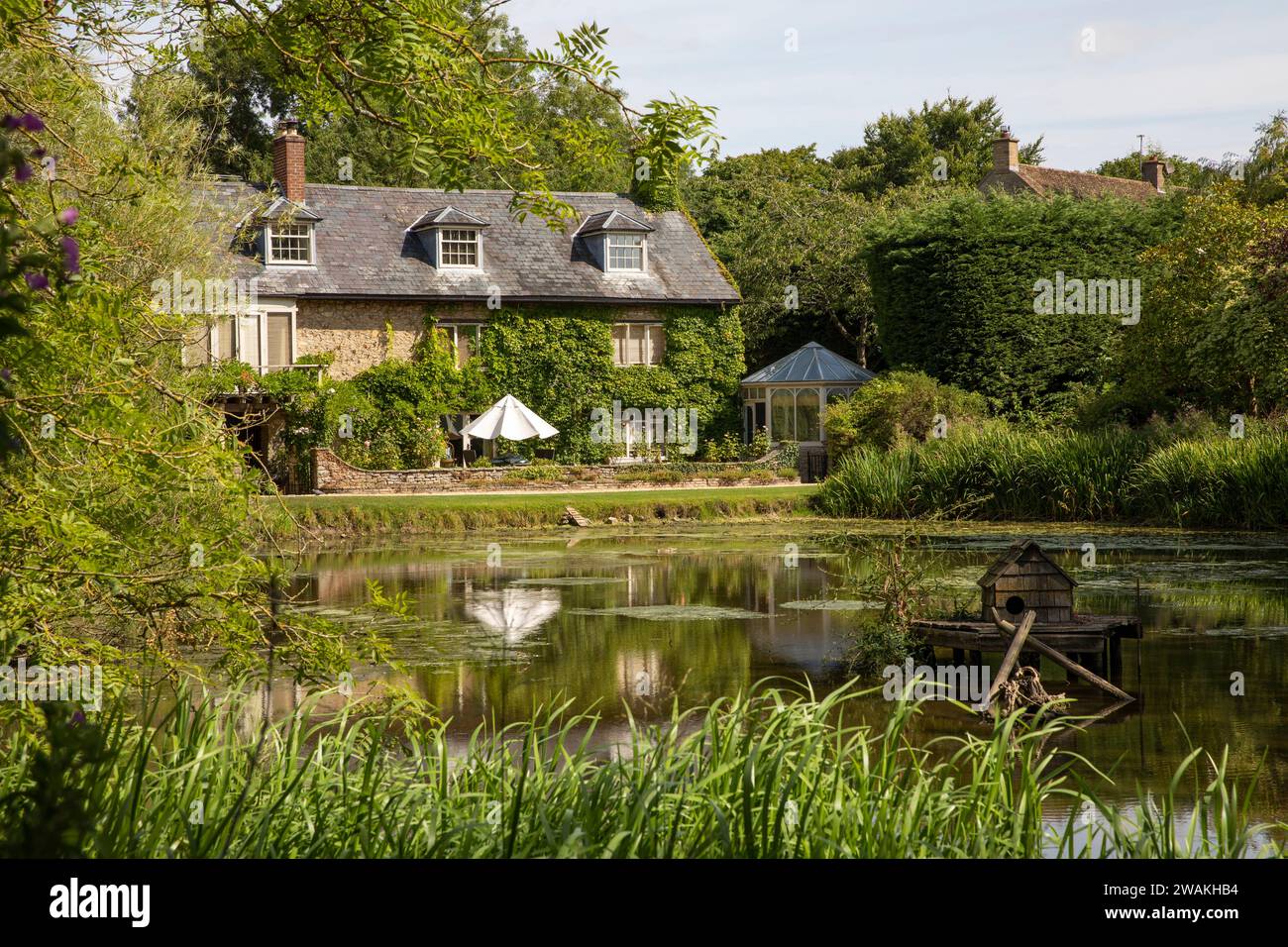 UK, England, Oxfordshire, Fringford, house at edge of village pond ...