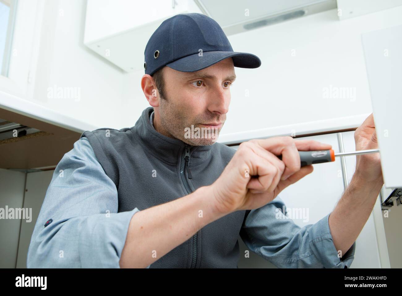 handyman working in kitchen using screwdriver Stock Photo - Alamy