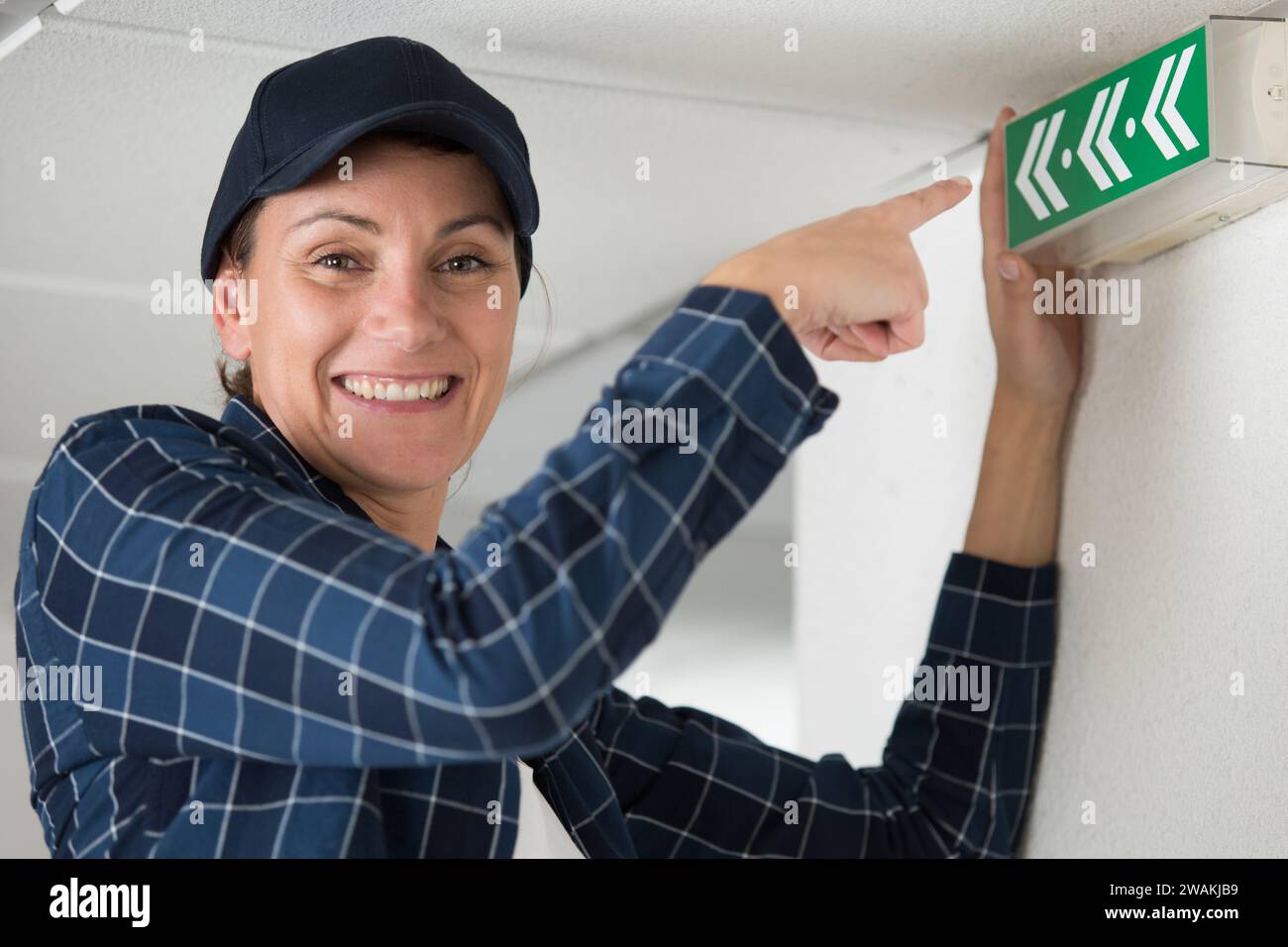 happy woman technician pointing at exit sign Stock Photo - Alamy