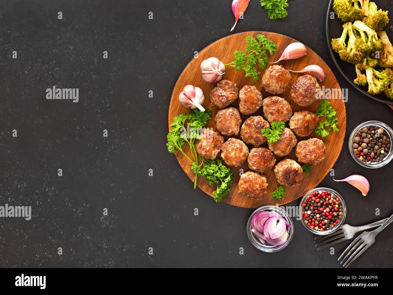 Roasted meatballs on cutting board over black stone background with ...