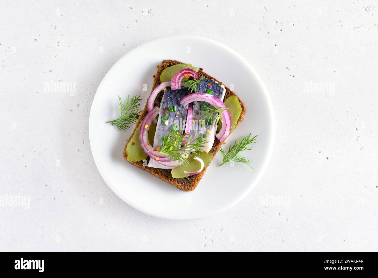 Sandwich with herring fish and pickles cucumbers on white plate. Top ...