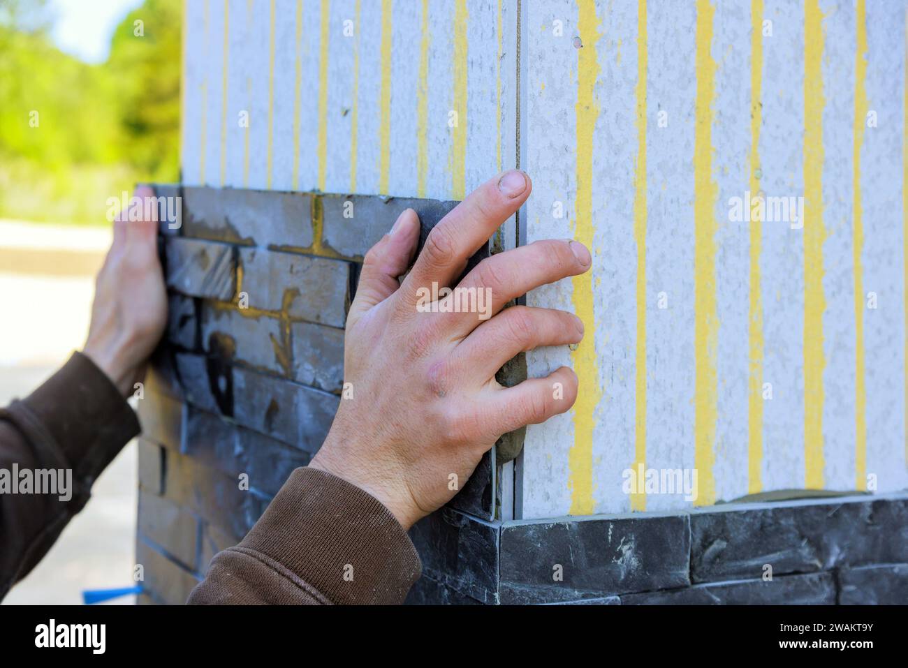 Tiler installation of facing tiles on building columns Stock Photo - Alamy