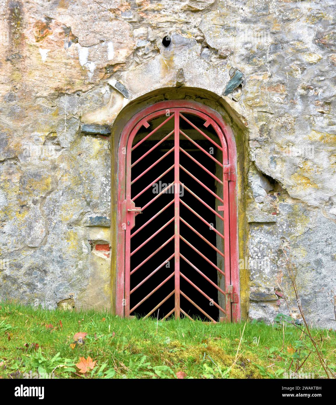 Old wall entrance of an abandoned castle closed with a red iron door ...