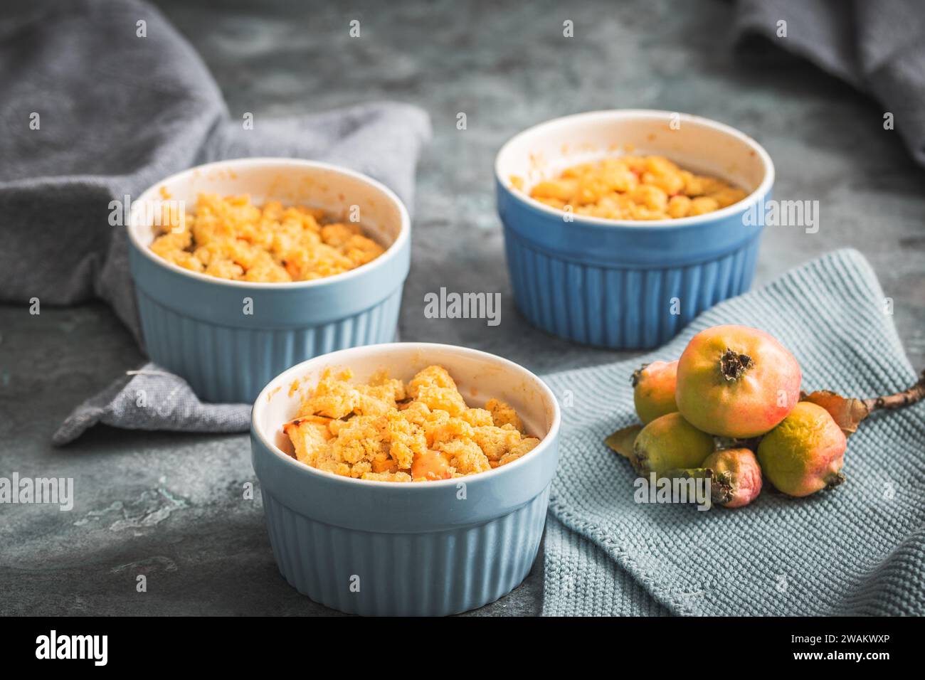 Apple crumble in small blue molds on a rustic gray table Stock Photo ...