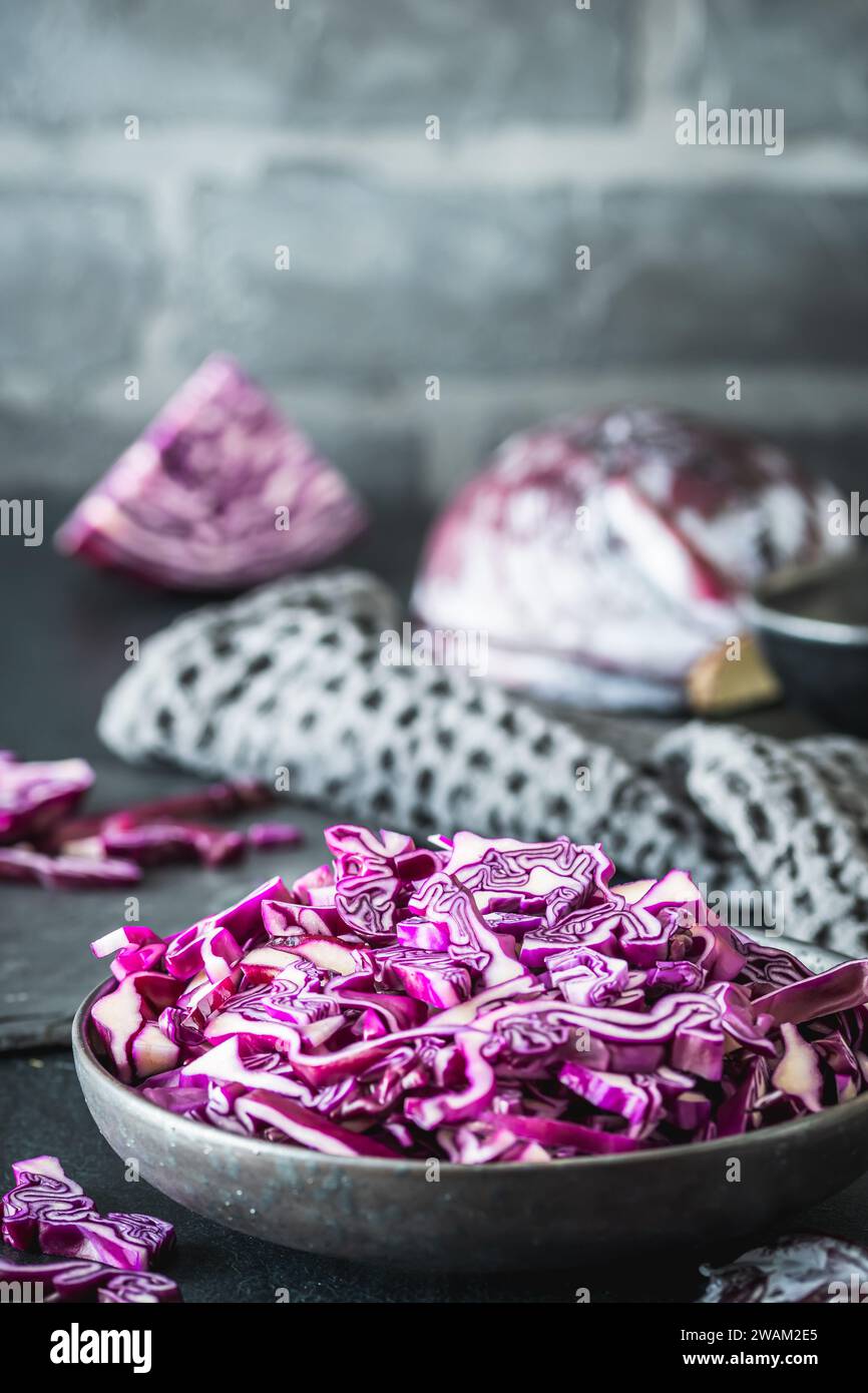 Fresh red cabbage, cut into pieces and strips, on gray table, vertical ...