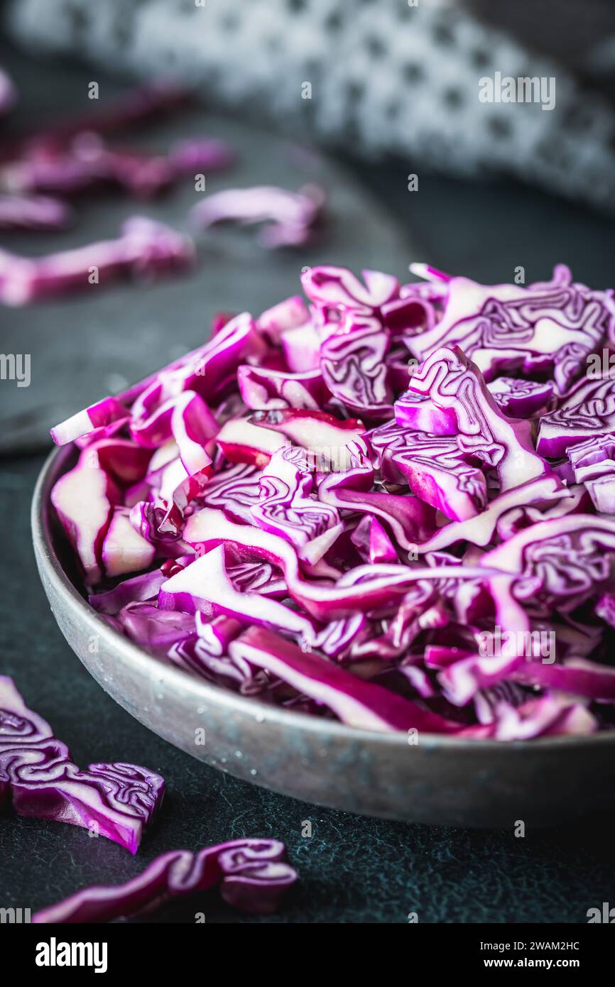 Fresh red cabbage, cut into pieces and strips, on gray table, vertical ...