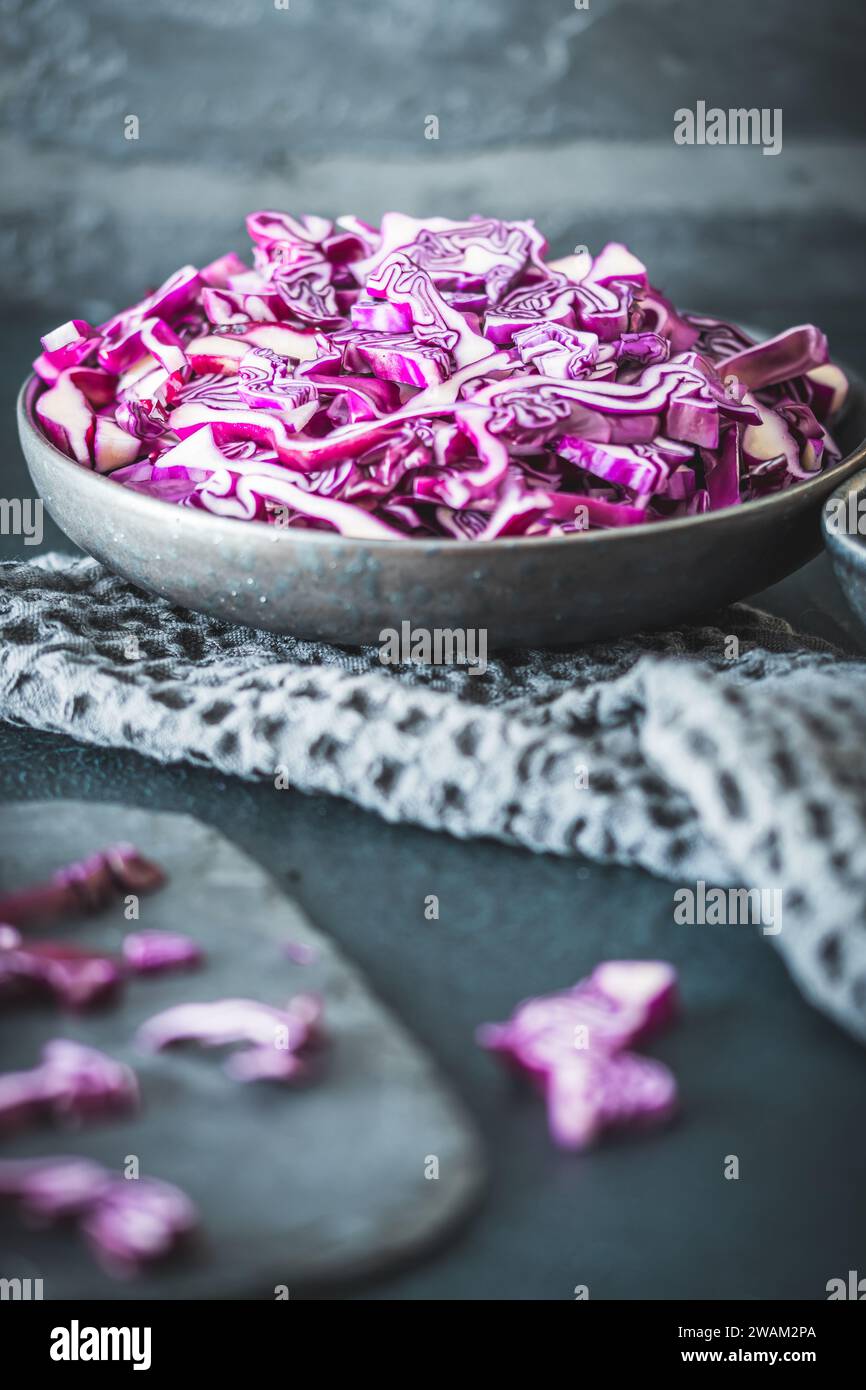Fresh red cabbage, cut into pieces and strips, on gray table, vertical ...
