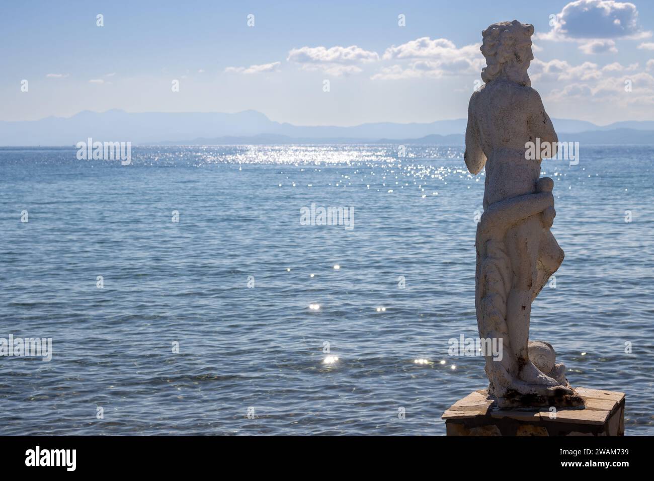 Calm and clean Ionian sea. Statue of Nereus in the harbor. Glittering ...
