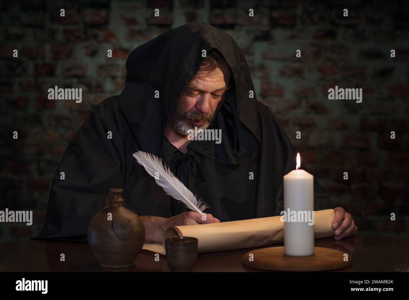 An old monk in his cell writes a message on parchment with a goose ...