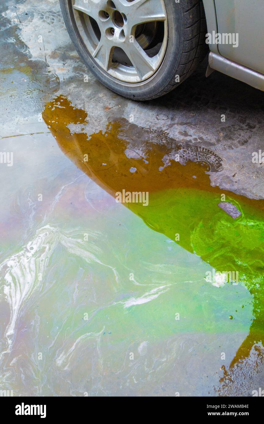 puddle of green coolant and brown technical liquids on the concrete ...