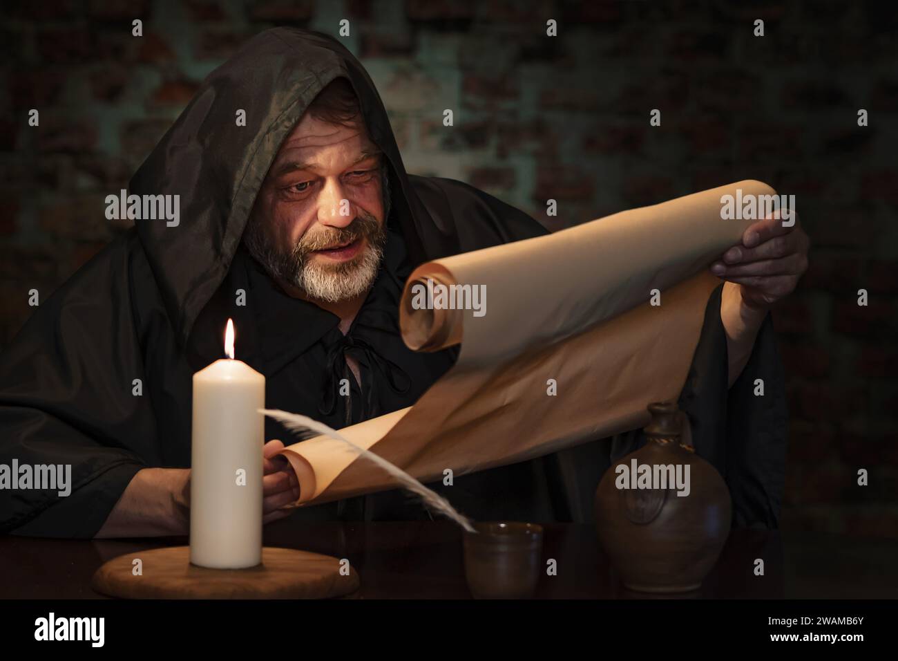 Emotional portrait of an elderly monk, by candlelight reading a message ...