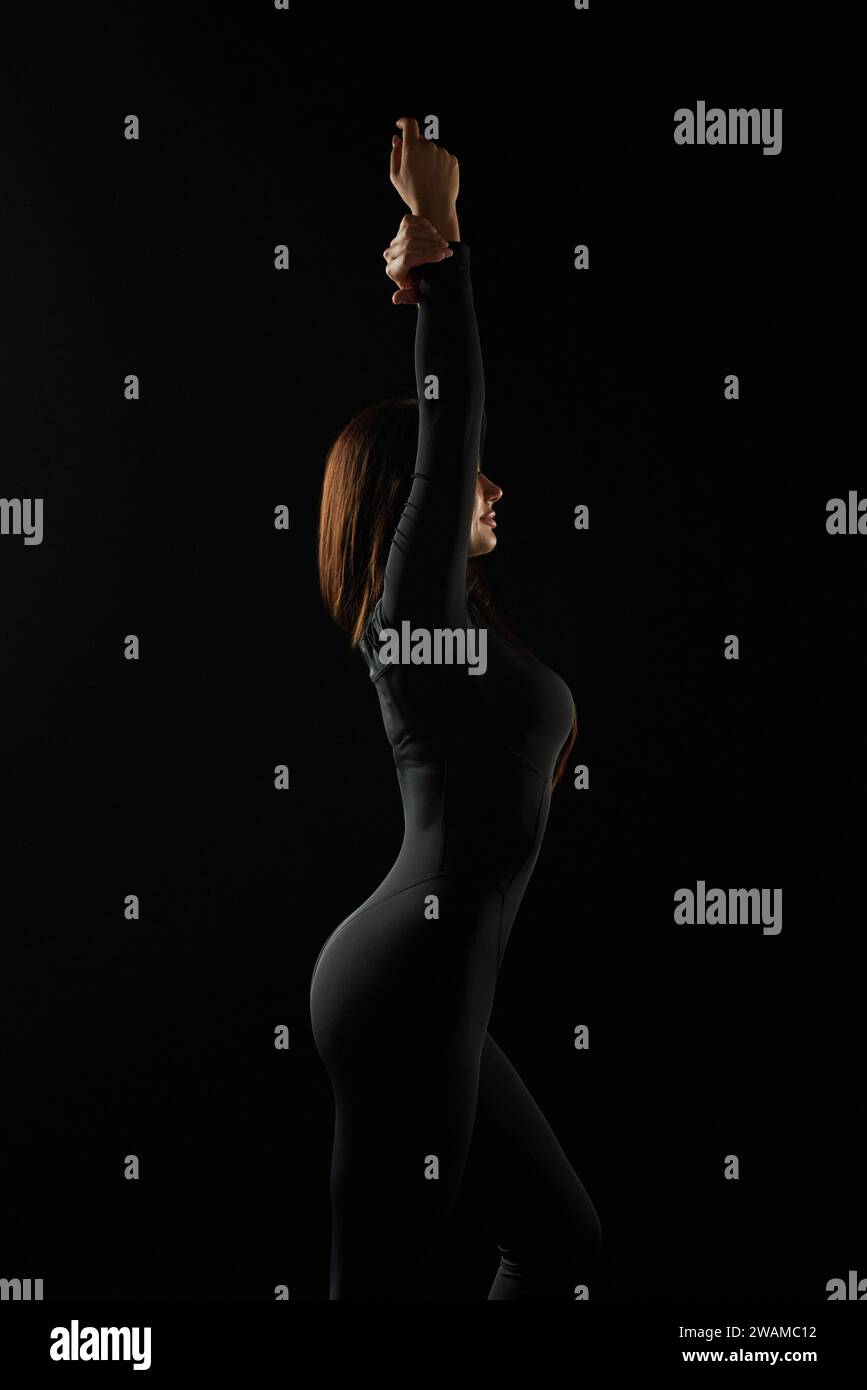 Silhouette of slim, sporty female wearing black, dancing in shadow ...