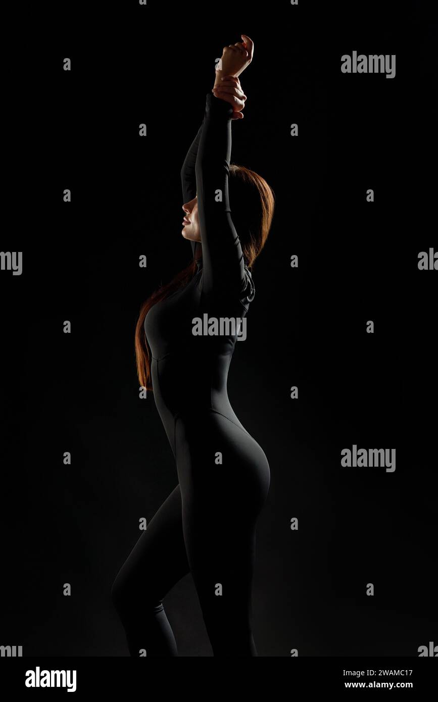 Attractive female wearing black, dancing in shadow. Side view of ...