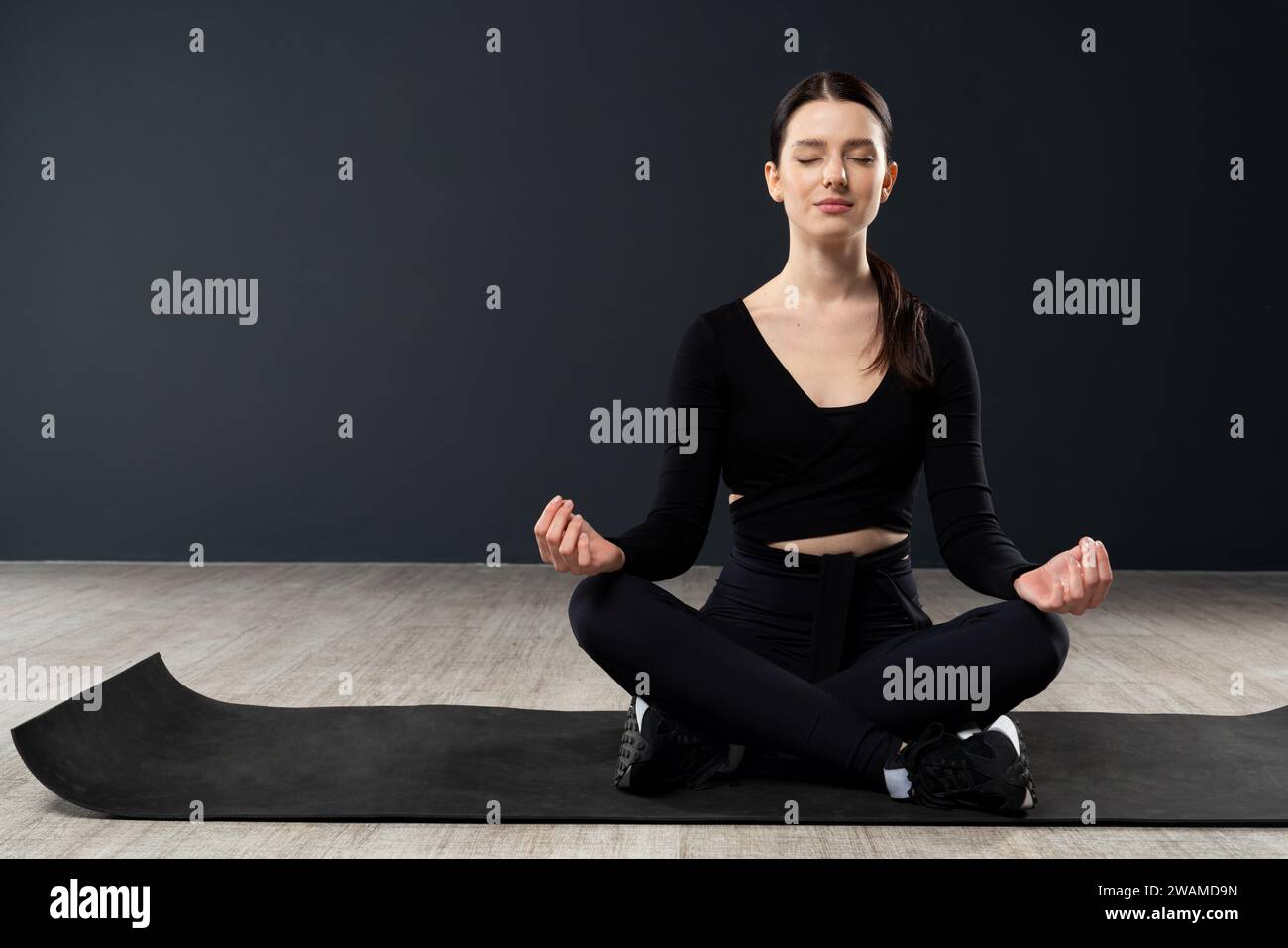 Focused, caucasian girl in black outfit sitting in easy pose ...