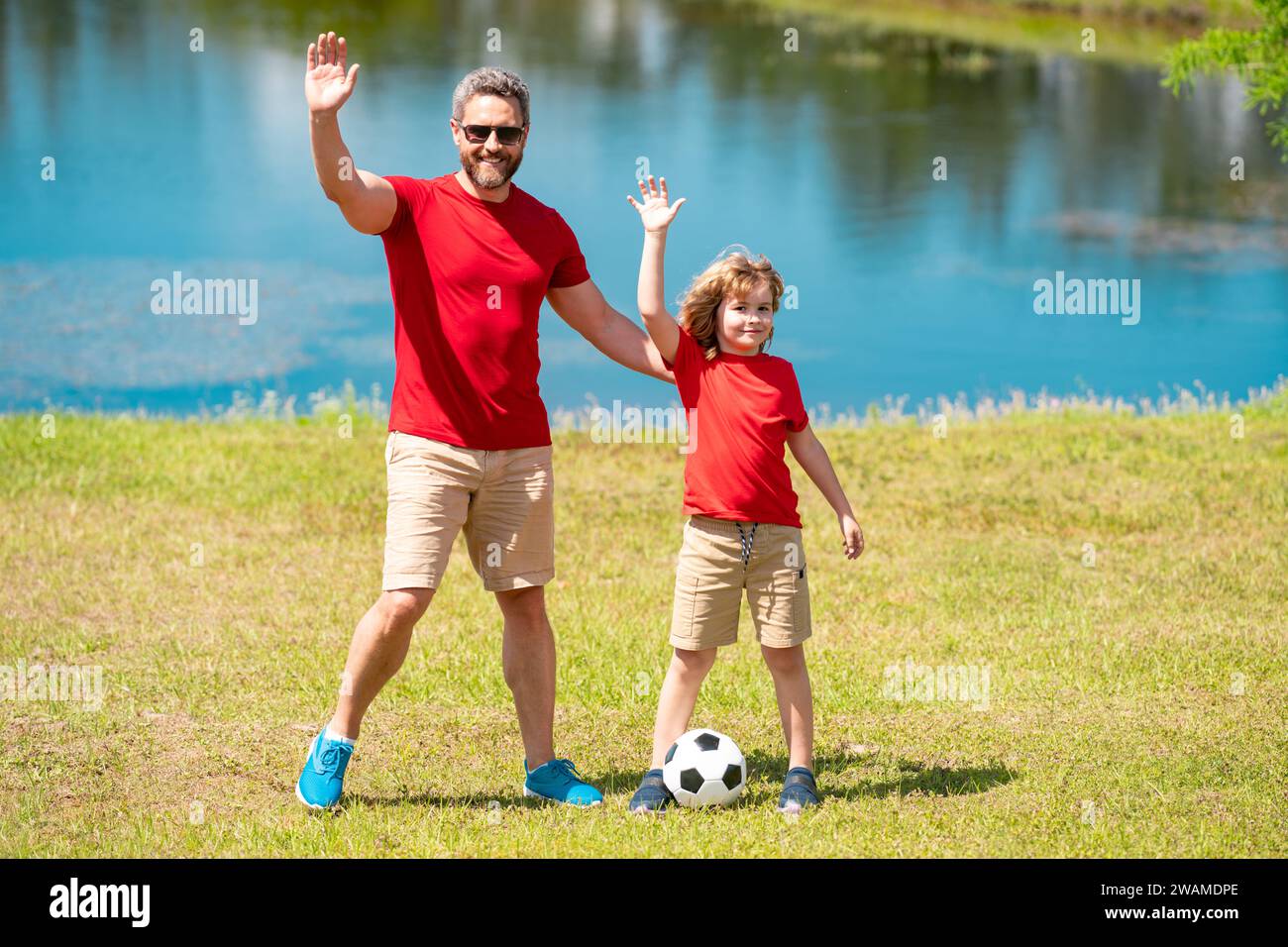 Dad and son playing football together on green meadow. Father and son ...
