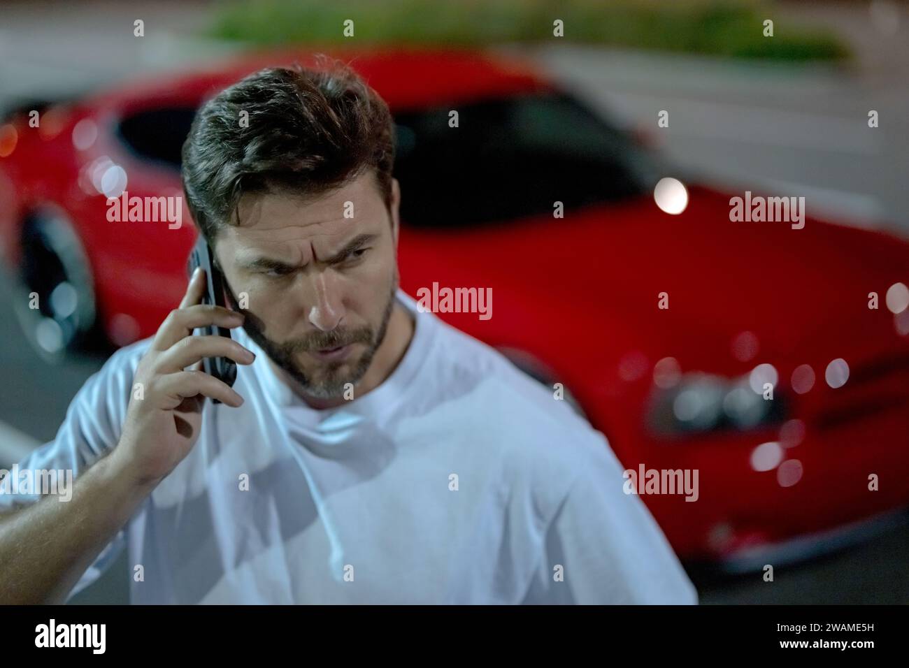 Aggressive talk. Serious driver man talking on phone on night urban ...