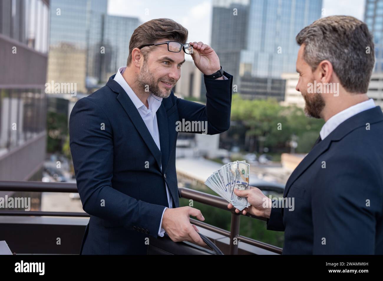 Businessman giving money to his partner outdoor. Businessman giving ...