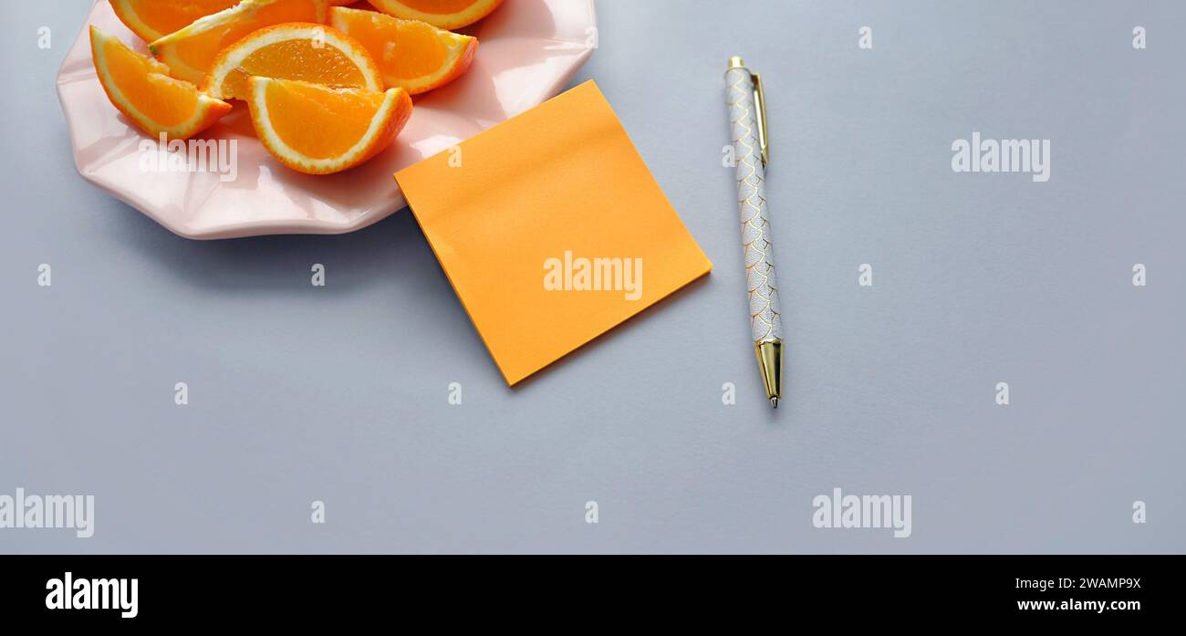 Composition with orange slices on a plate, sticky note and pen on a ...
