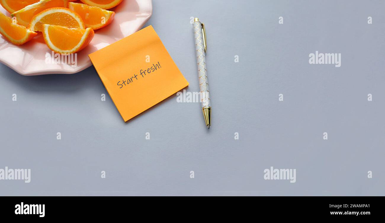 Composition with orange slices on a plate, sticky note and pen on a ...