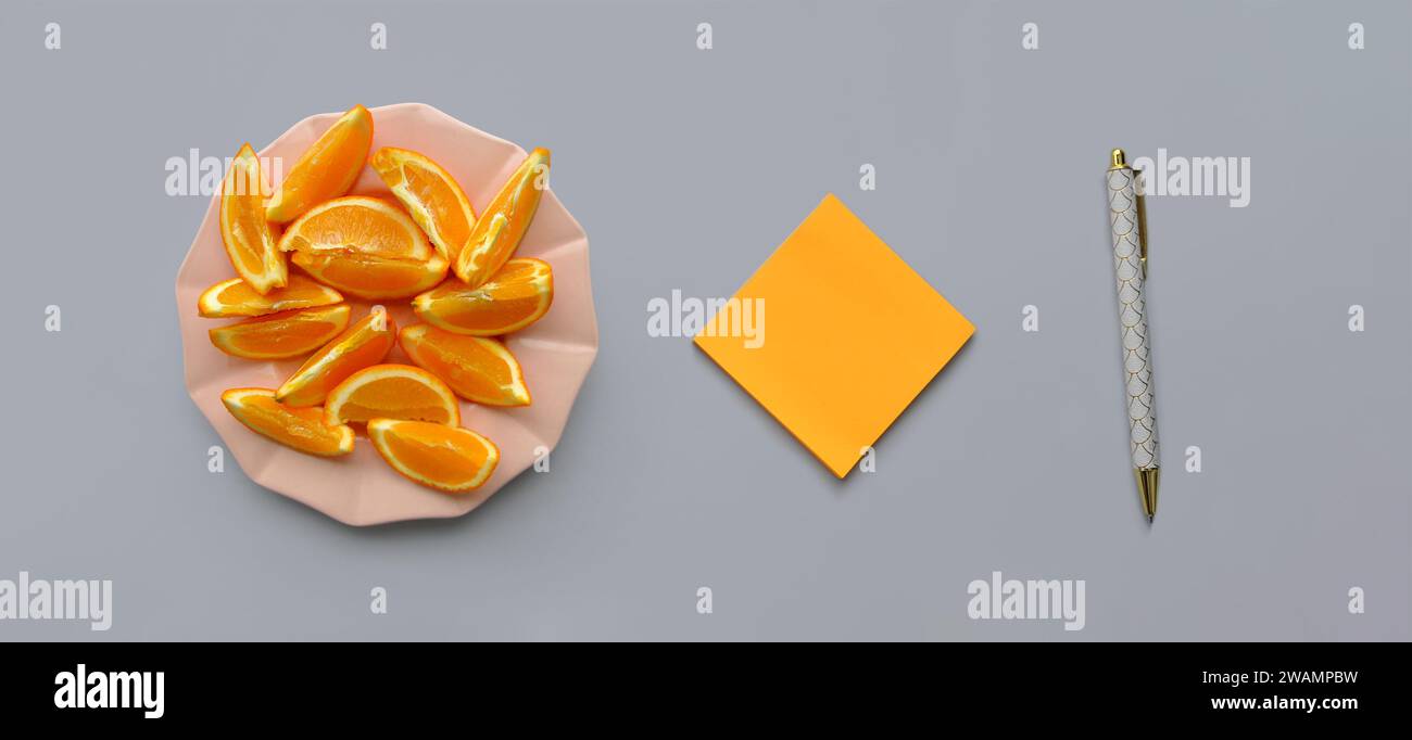 Composition with orange slices on a plate, sticky note and pen on a ...