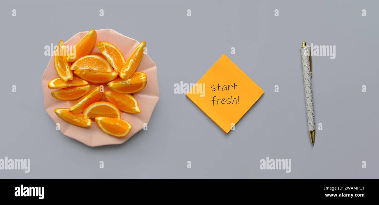 Composition with orange slices on a plate, sticky note and pen on a ...